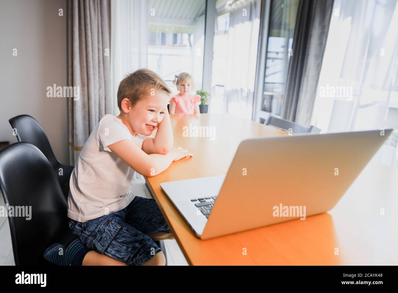 Small smiling kids brother and sister laugh and play laptop ...