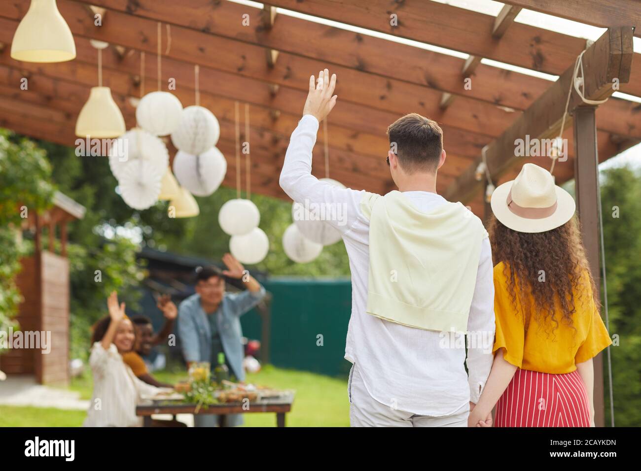Back view portrait of young couple waving to friends while leaving ...