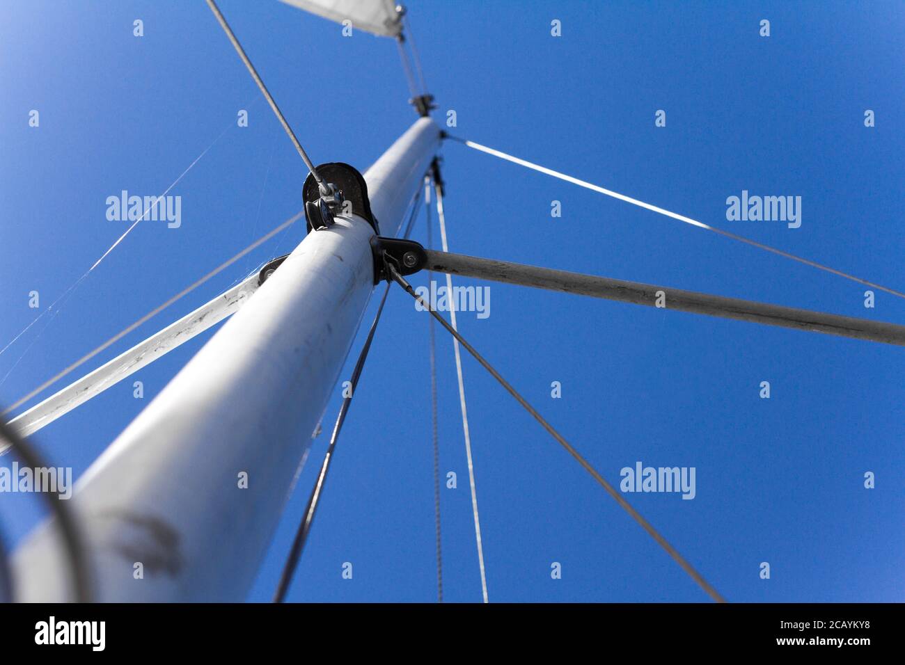 Bottom view of mast and sail of yacht on blue sky background, selective ...