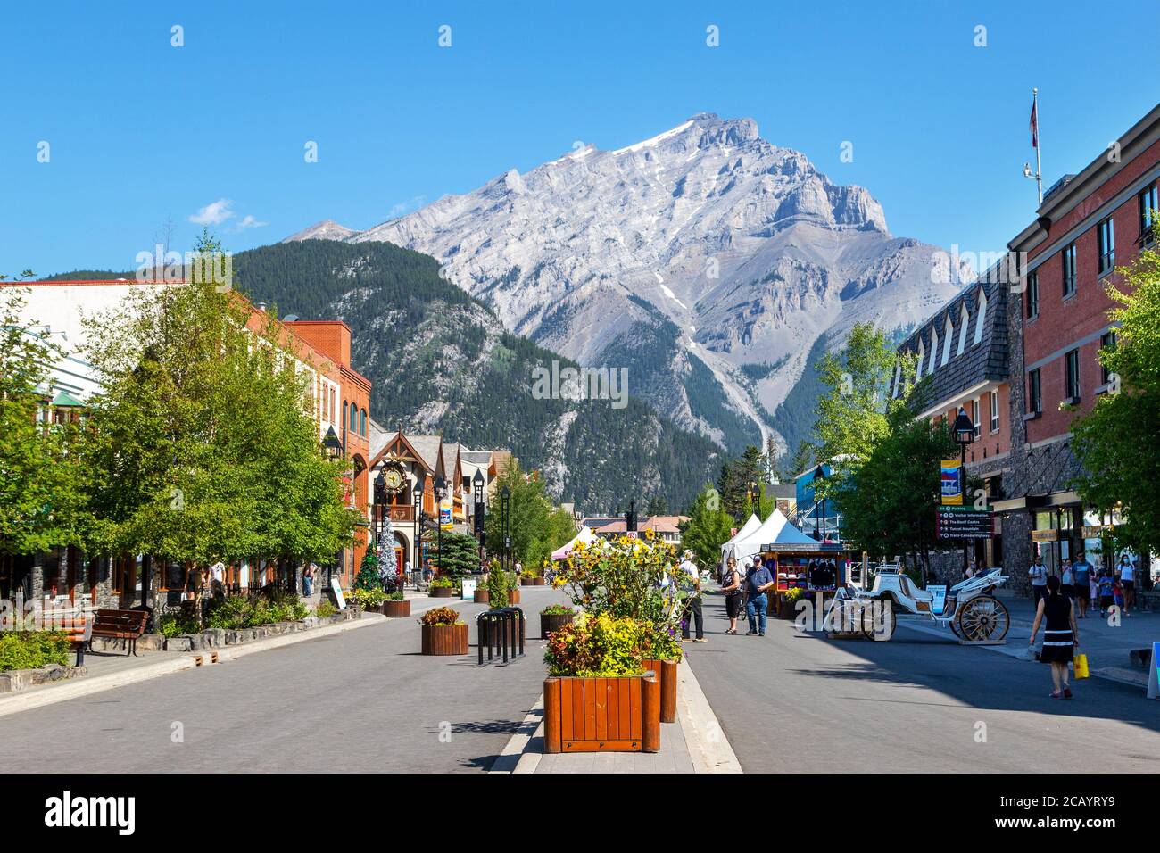BANFF, CANADA - JULY 29, 2020: Tourists walk along Banff Avenue in Banff National Park with ...