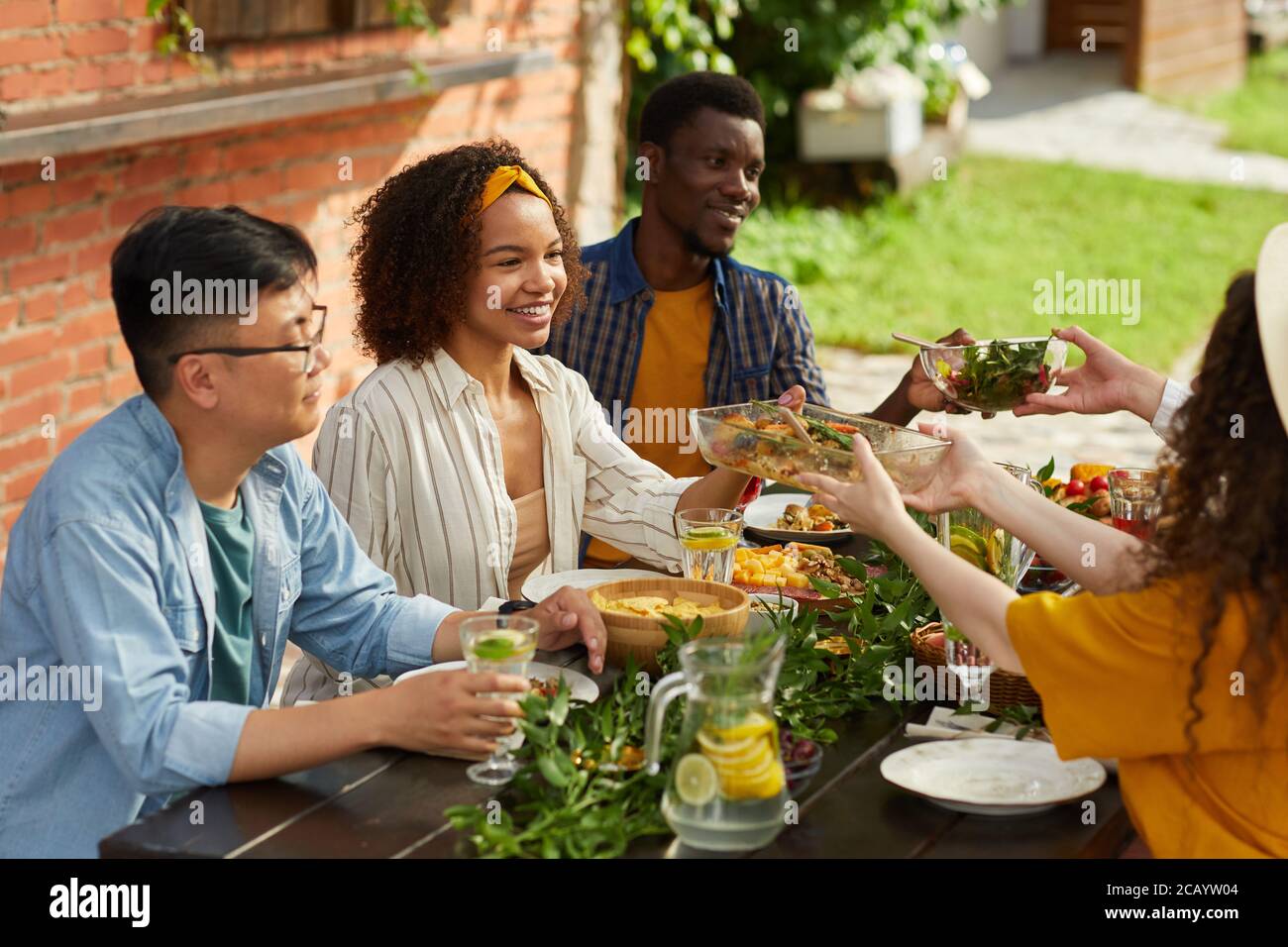 Multi-ethnic group of people sharing food while enjoying dinner with ...