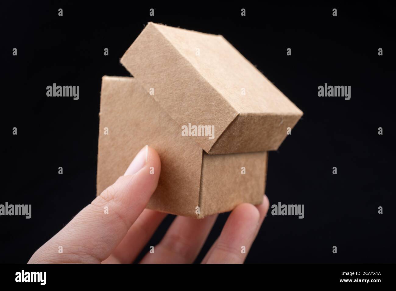 Hand holding a brown cardboard box on black backgrounds Stock Photo - Alamy
