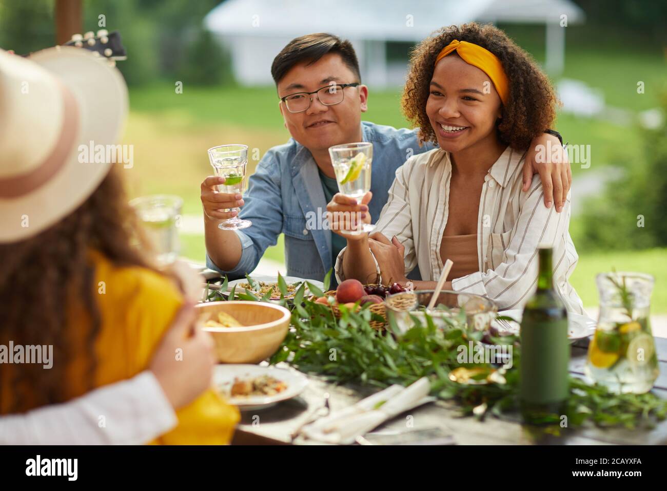 Portrait of mixed-race young couple embracing while sitting table ...