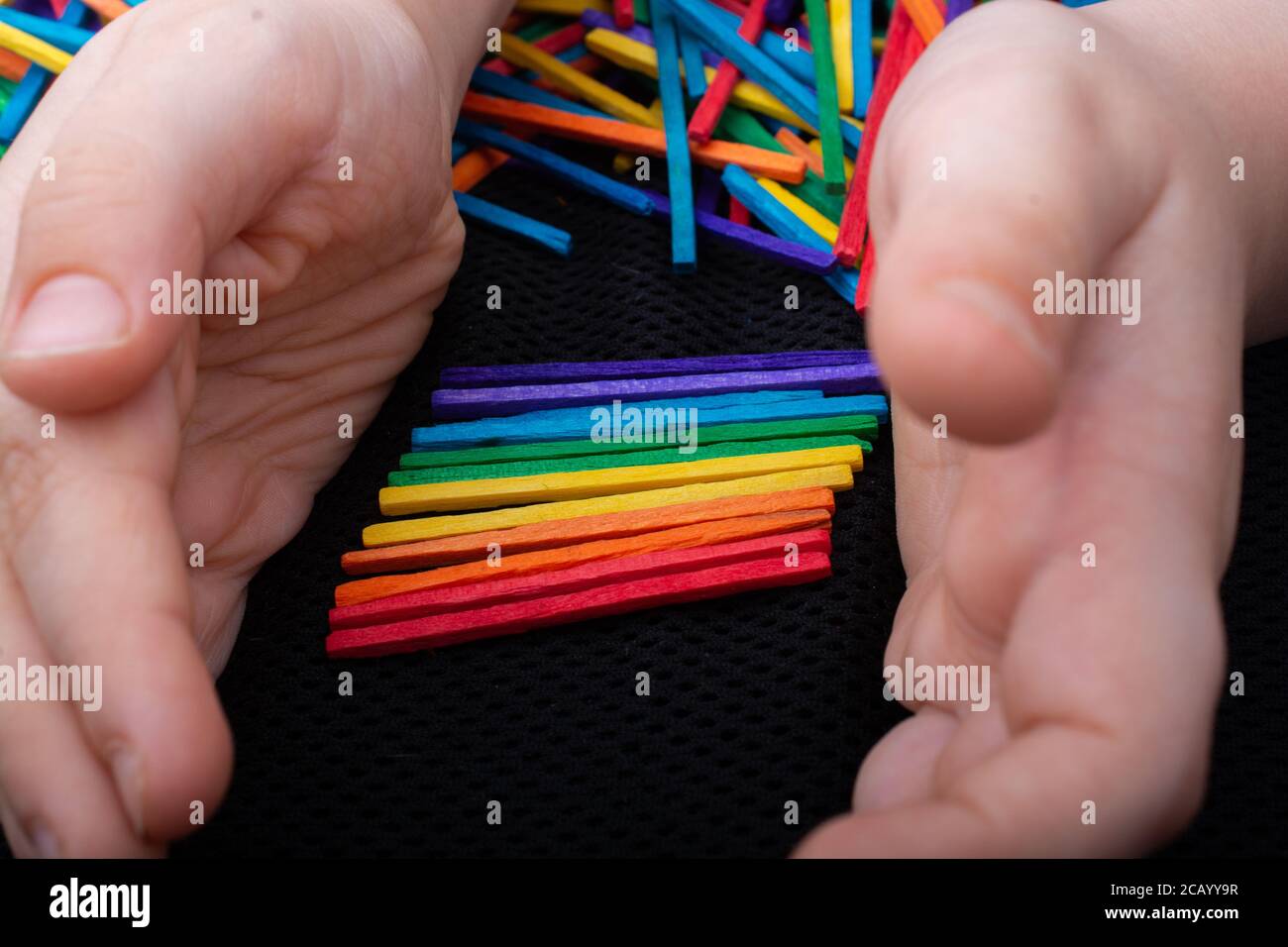 Kid playing with coloured wooden sticks for creativity on white ...
