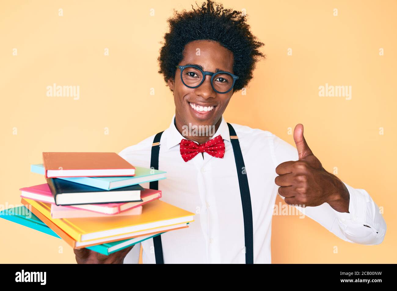 Handsome african american nerd man with afro hair holding books smiling ...