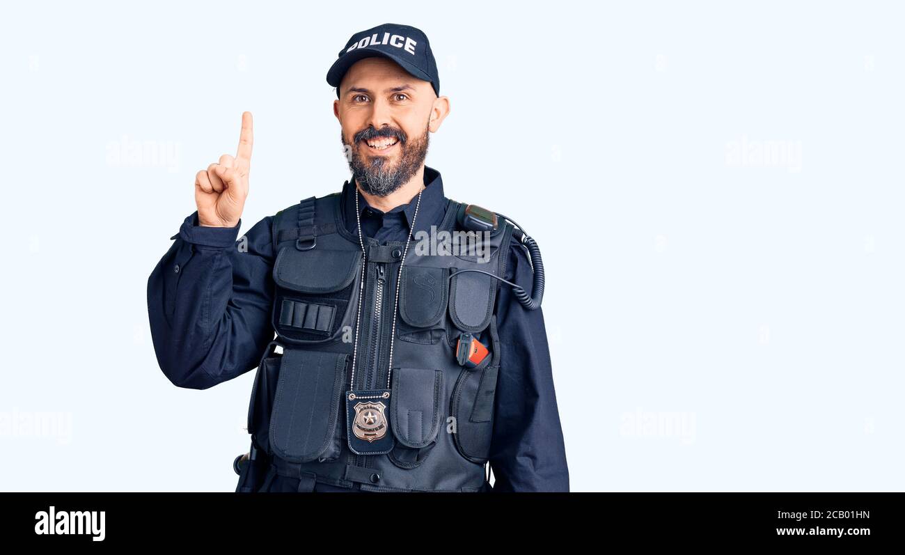 Young handsome man wearing police uniform pointing finger up with ...
