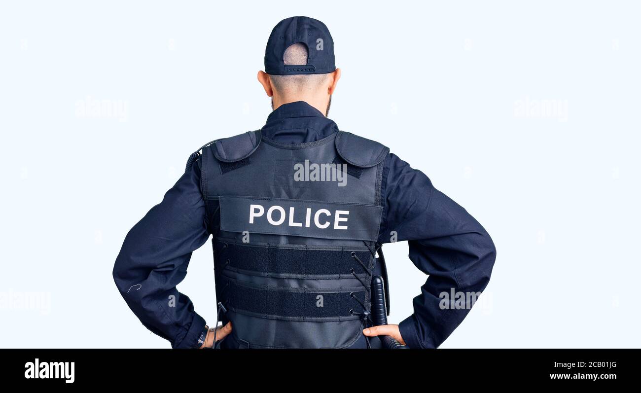 Young handsome man wearing police uniform standing backwards looking ...