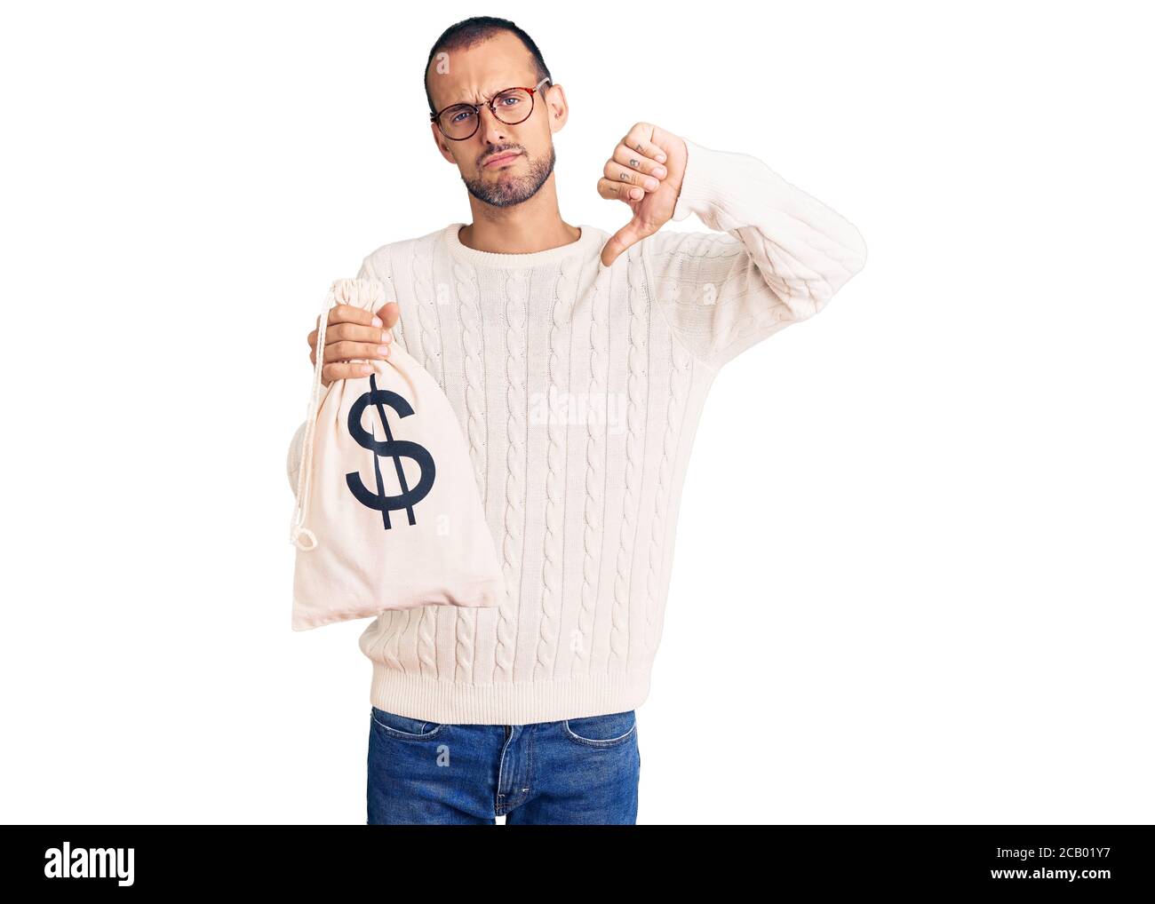 Young handsome man holding money bag with dollar symbol with angry face ...