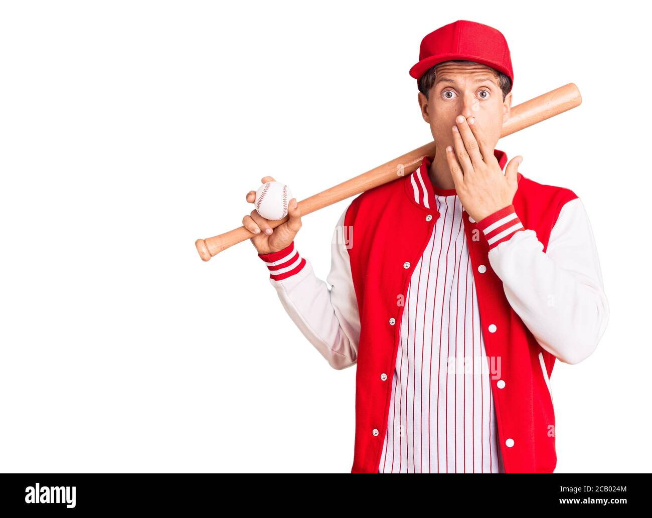 Young handsome man playing baseball holding bat and ball covering mouth ...