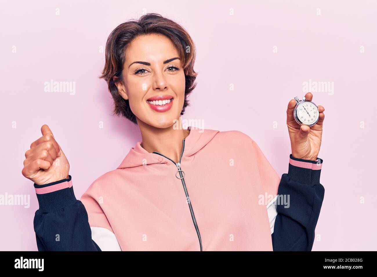 Young beautiful woman holding stopwatch smiling happy and positive ...