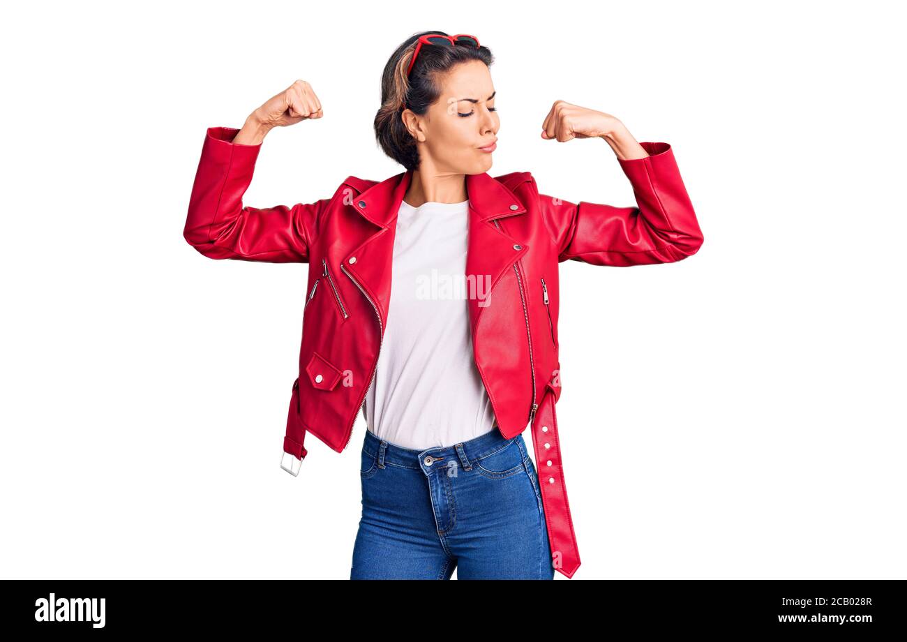 Young beautiful woman wearing red leather jacket showing arms muscles ...