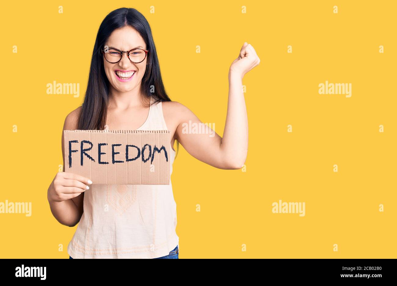 Young beautiful caucasian woman holding freedom banner screaming proud ...