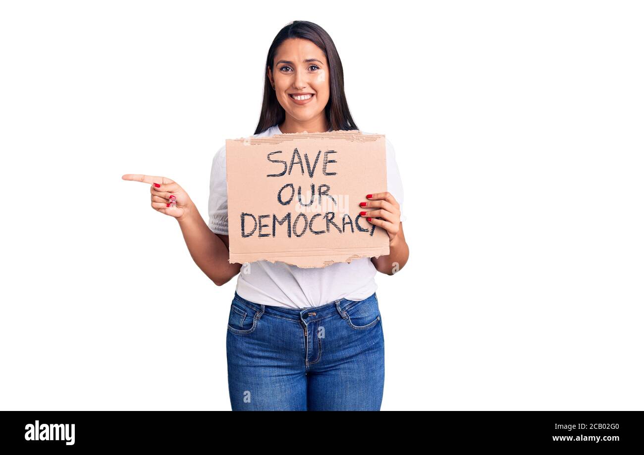 Young beautiful woman holding save our democracy cardboard banner ...
