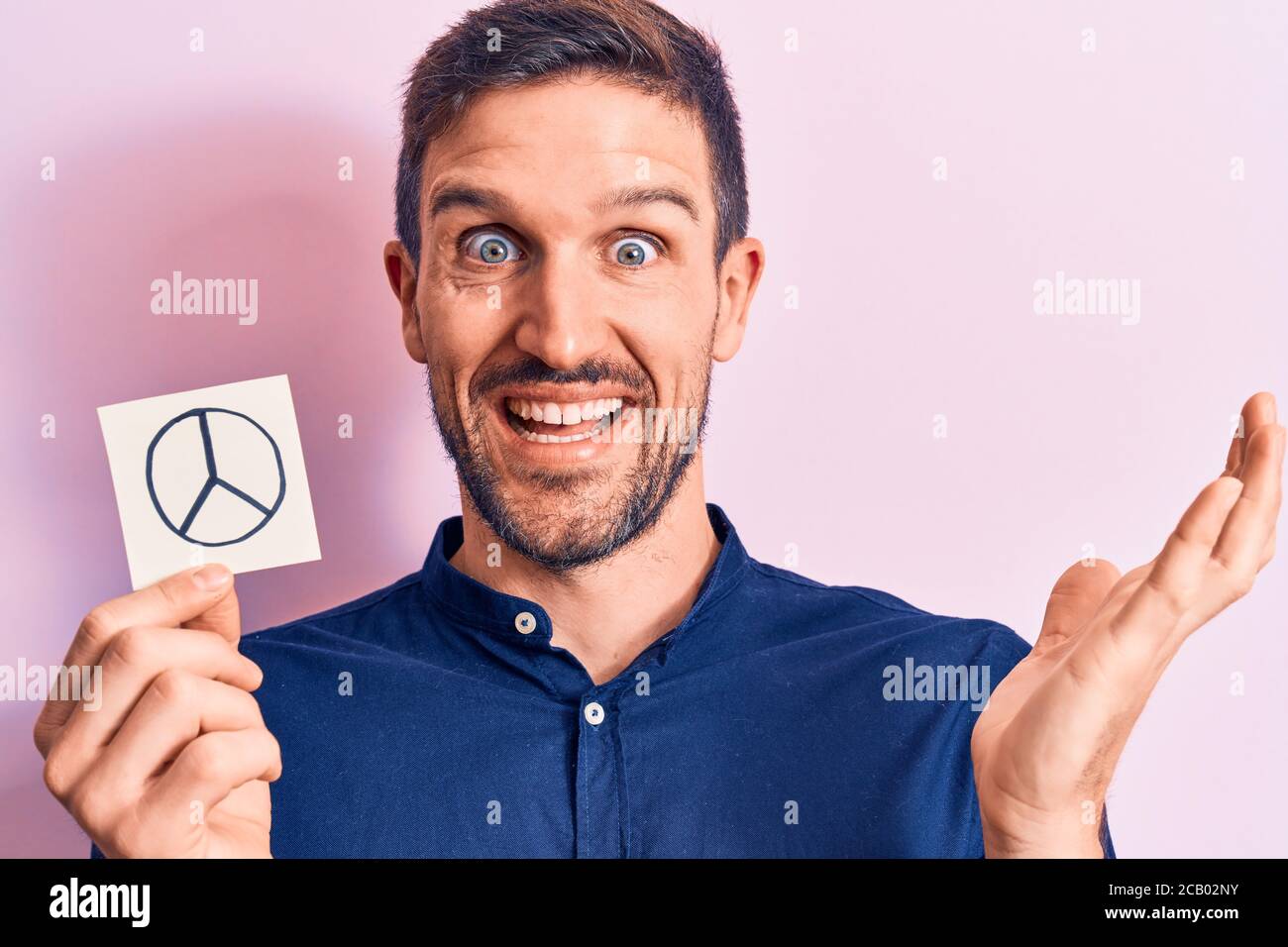 Young handsome man holding reminder with peace symbol over isolated ...