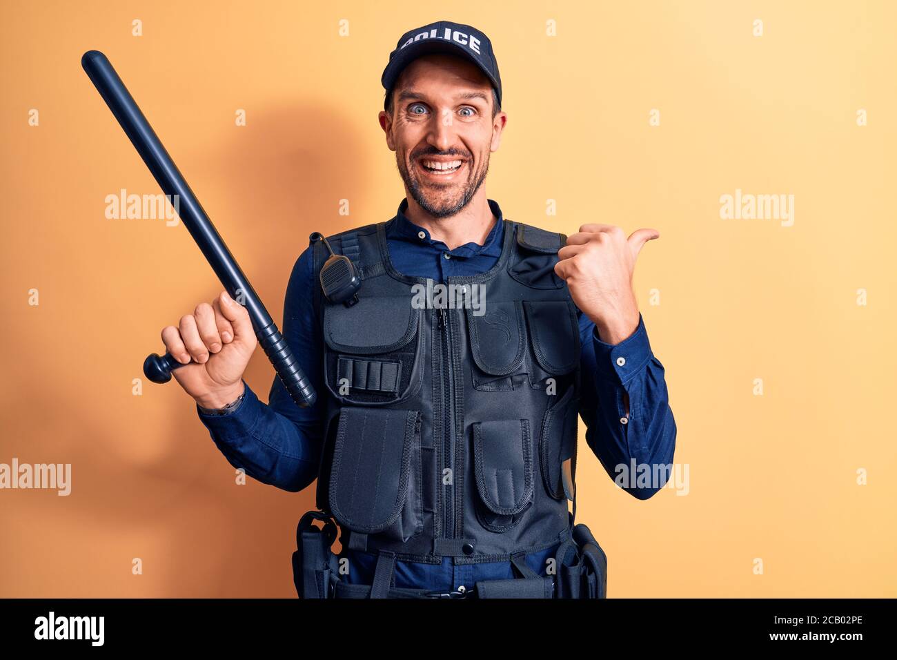Handsome policeman wearing uniform and bulletprof holding baton over ...