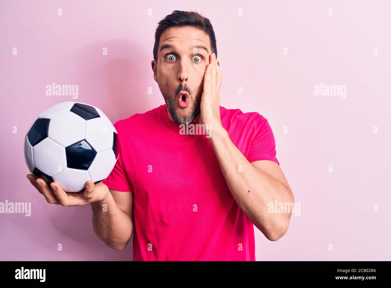 Young handsome player man playing soccer holding football ball over ...