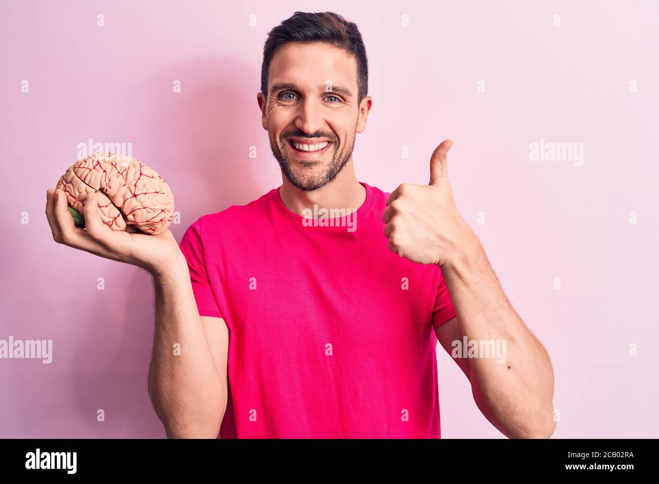Young handsome man asking for care memory holding brain over isolated ...