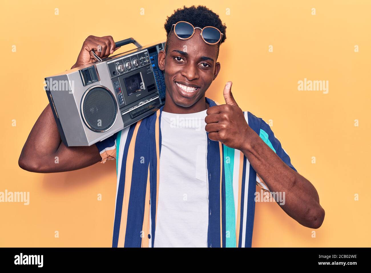 Young african american man holding boombox, listening to music smiling ...