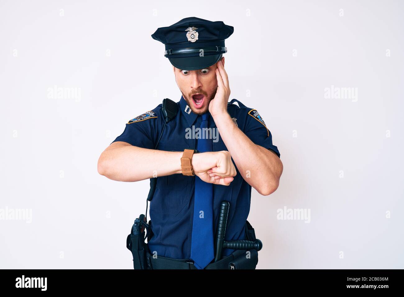 Young caucasian man wearing police uniform looking at the watch time ...