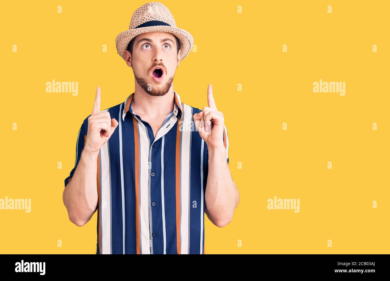 Young handsome caucasian man wearing summer hat amazed and surprised ...