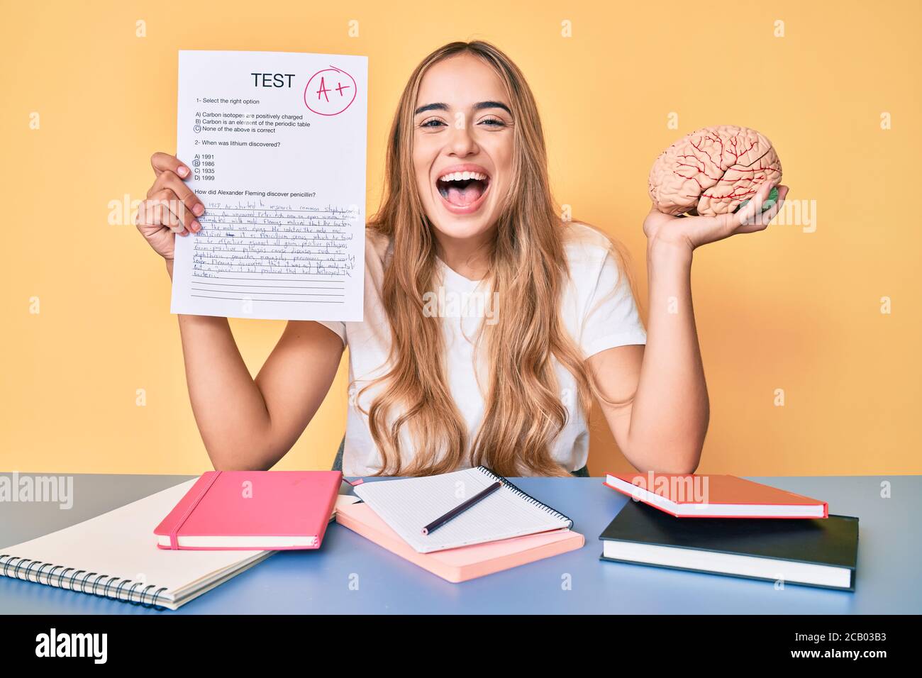 Young beautiful blonde woman holding brain and passed test smiling and ...