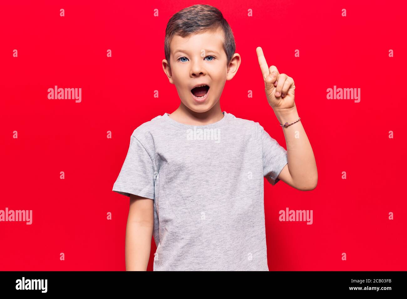 Cute blond kid wearing casual clothes pointing finger up with ...