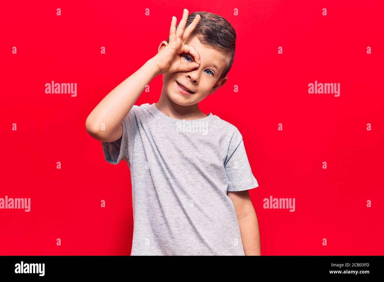 Cute blond kid wearing casual clothes smiling happy doing ok sign with ...