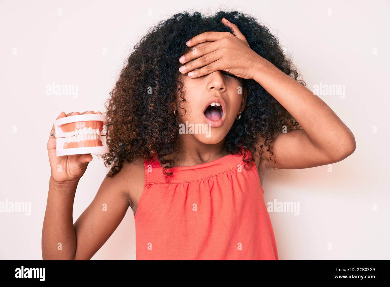 African american child with curly hair holding denture stressed and ...