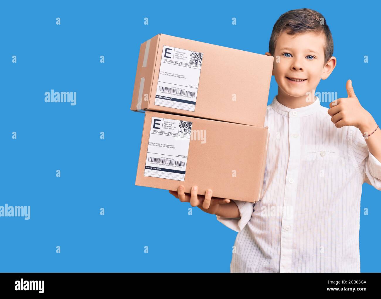Cute blond kid holding delivery package smiling happy and positive ...
