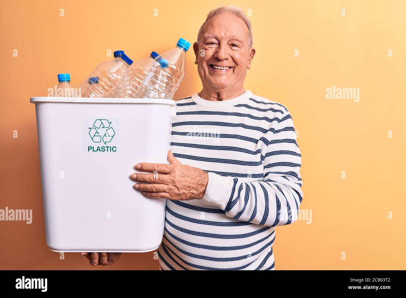 Senior handsome grey-haired man recycling holding wastebasket full of ...