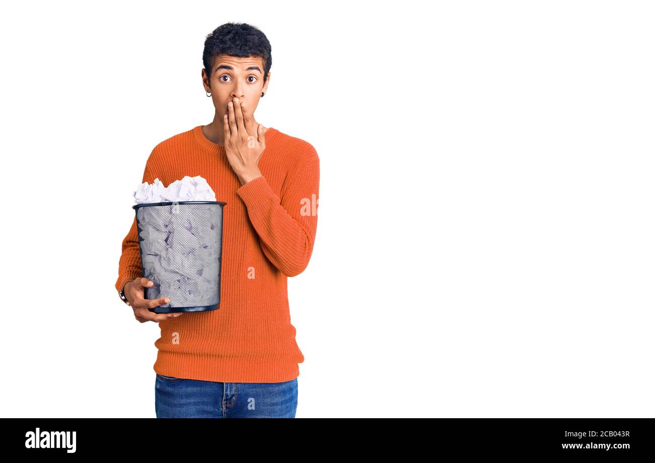 Young african amercian man holding paper bin full of crumpled papers ...