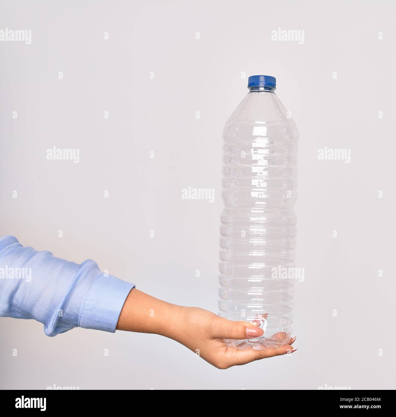 Hand of caucasian young woman holding plastic bottle to recycle over ...