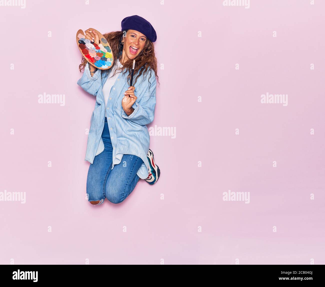 Young beautiful curly artist woman with tattoo wearing french beret ...