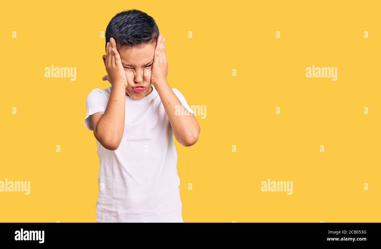 Little cute boy kid wearing casual white tshirt suffering from headache ...