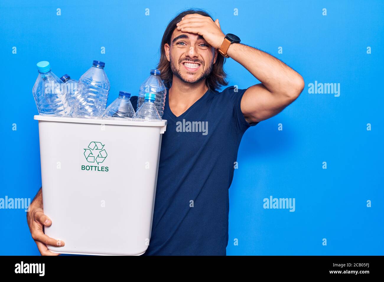 Young handsome man holding recycling wastebasket with plastic bottles ...