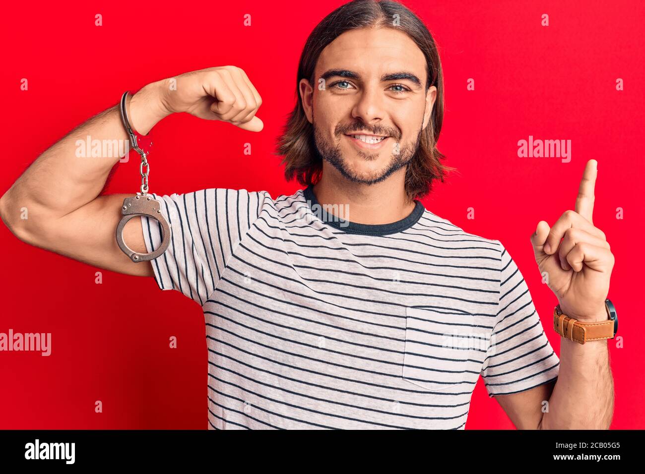 Young handsome man wearing prisoner handcuffs surprised with an idea or ...