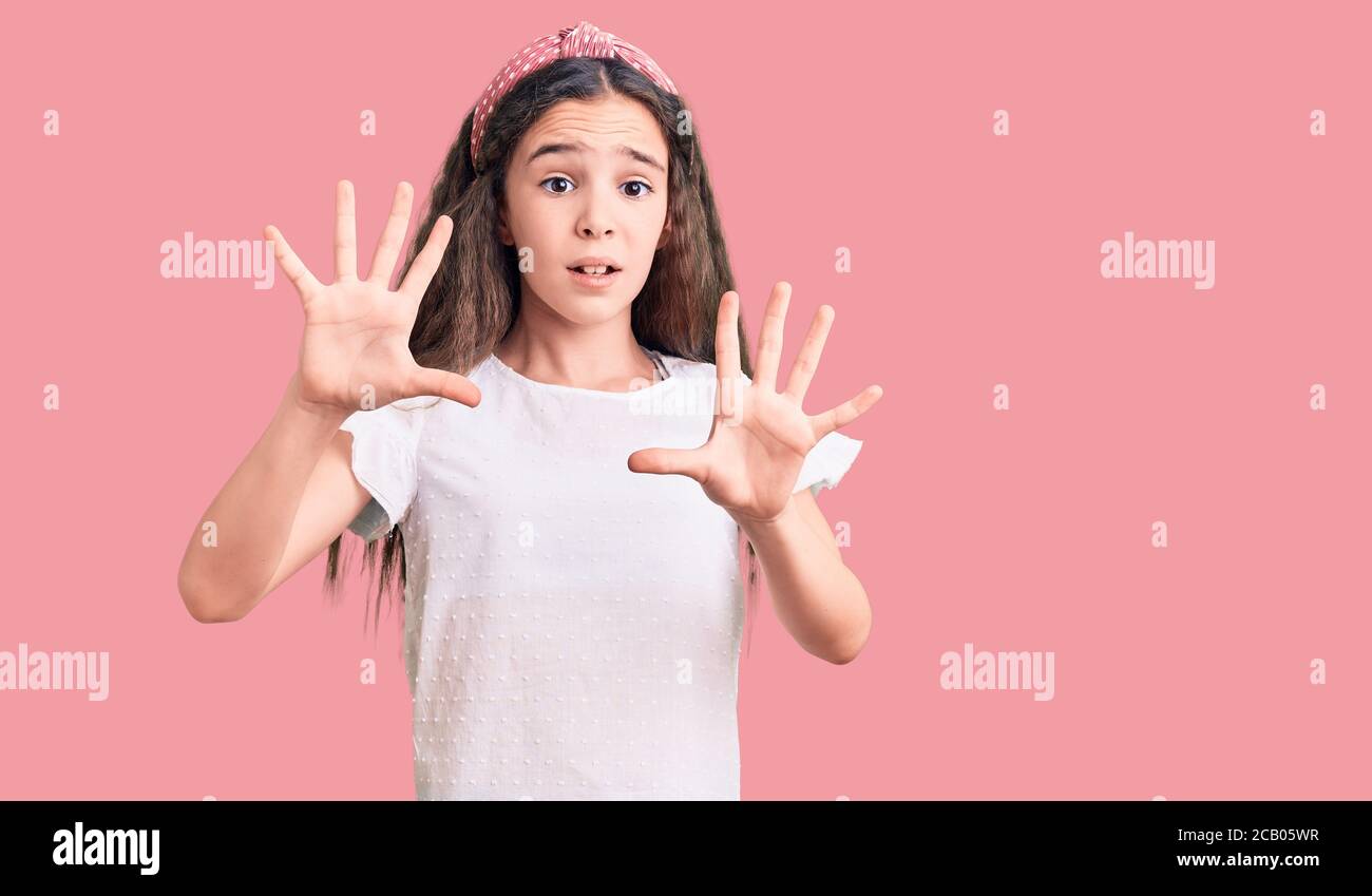 Cute hispanic child girl wearing casual white tshirt afraid and ...