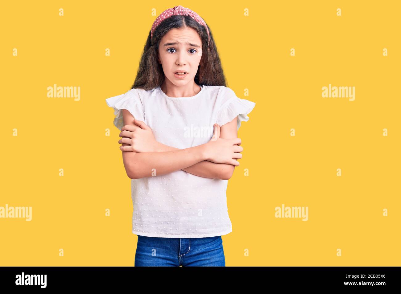 Cute hispanic child girl wearing casual white tshirt shaking and ...