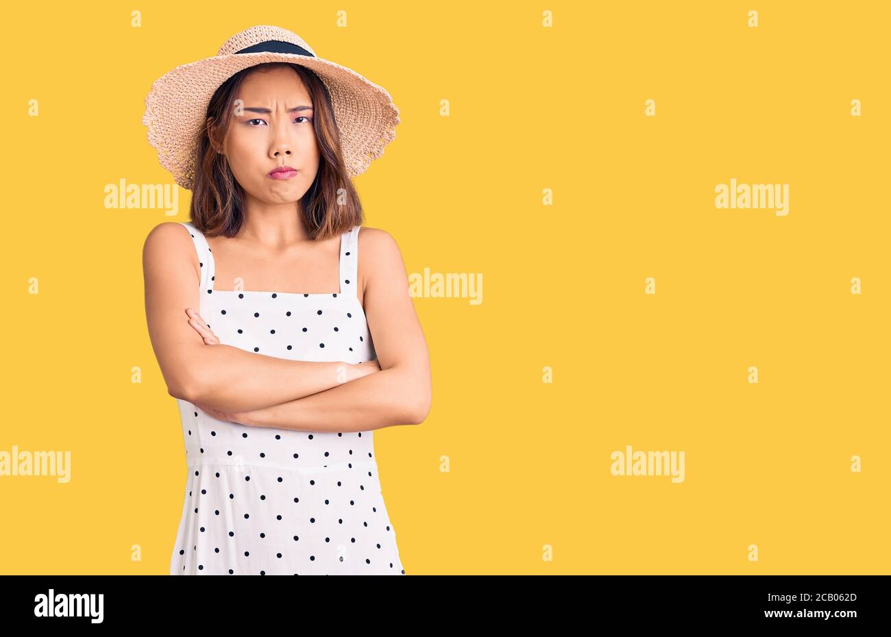Young beautiful chinese girl wearing summer hat skeptic and nervous ...