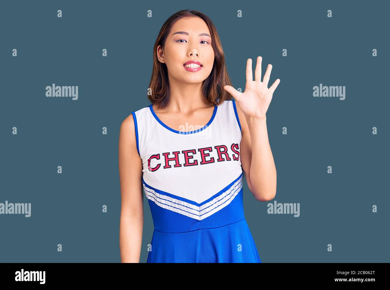 Young beautiful chinese girl wearing cheerleader uniform showing and ...