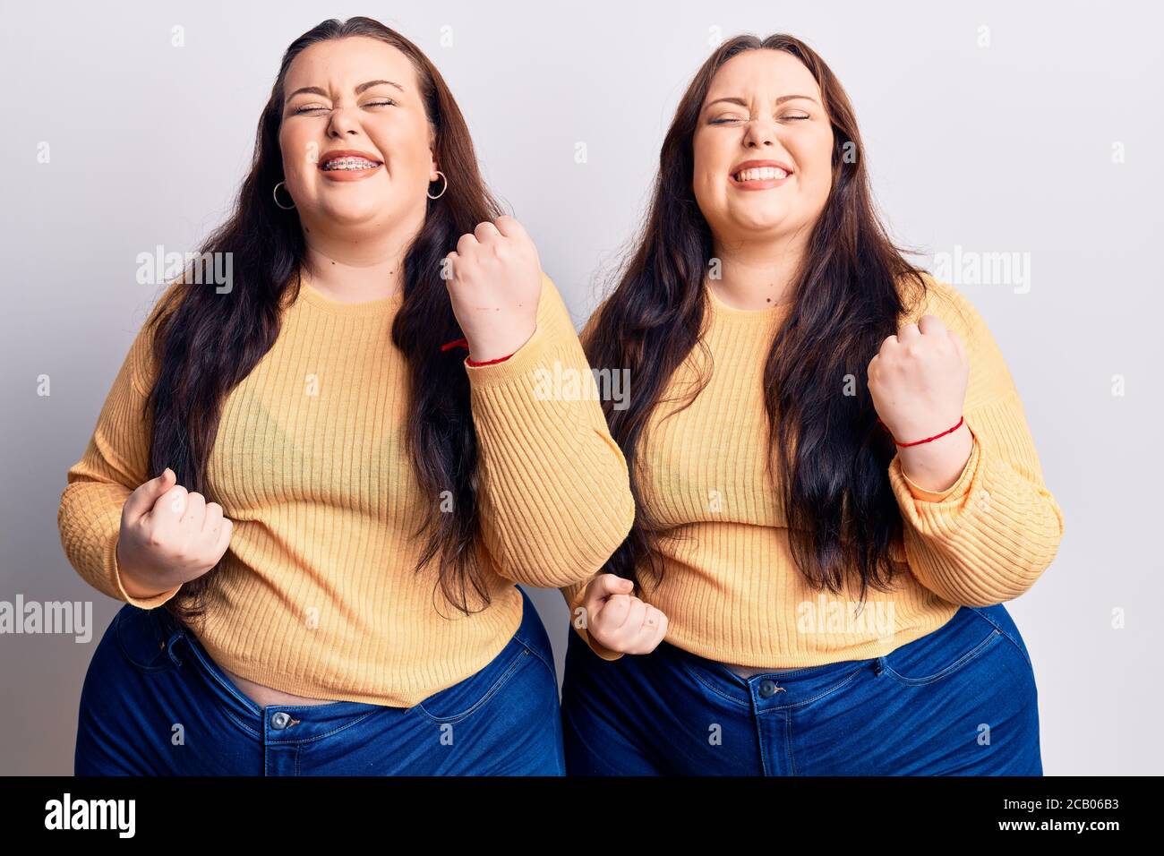 Young plus size twins wearing casual clothes celebrating surprised and ...