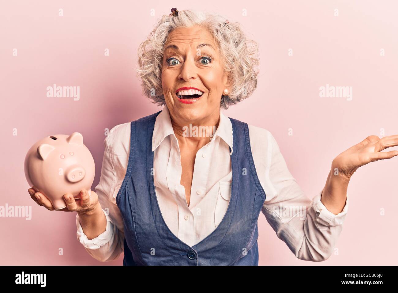Senior grey-haired woman holding piggy bank celebrating achievement ...