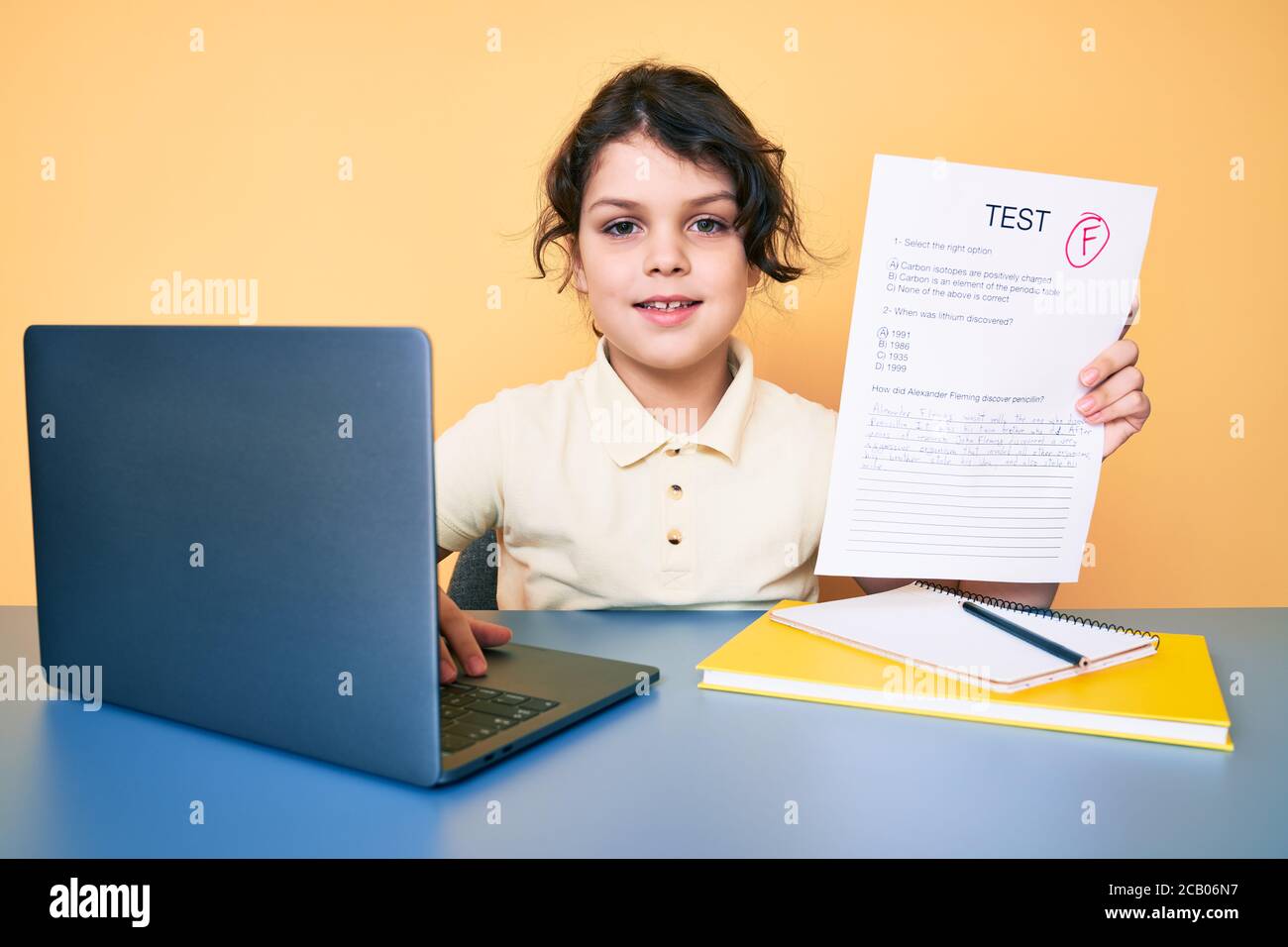 Cute hispanic child showing failed exam sitting on the desk looking ...
