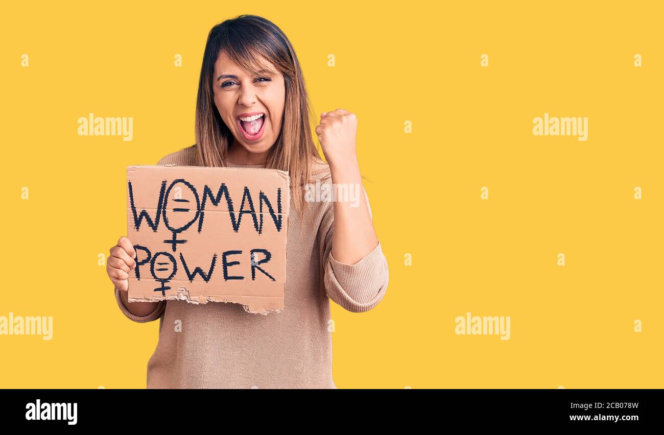 Young beautiful woman holding woman power banner screaming proud ...