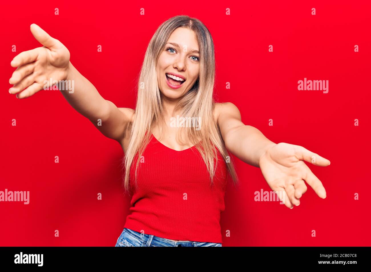 Young blonde woman wearing casual clothes looking at the camera smiling ...