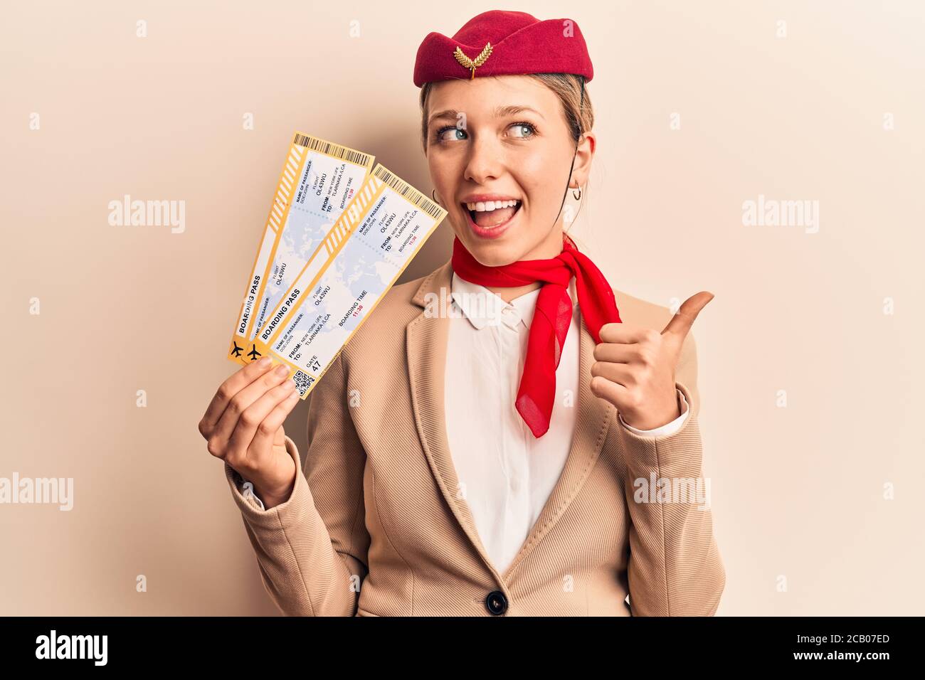 Young beautiful blonde girl wearing stewardess uniform holding boarding ...