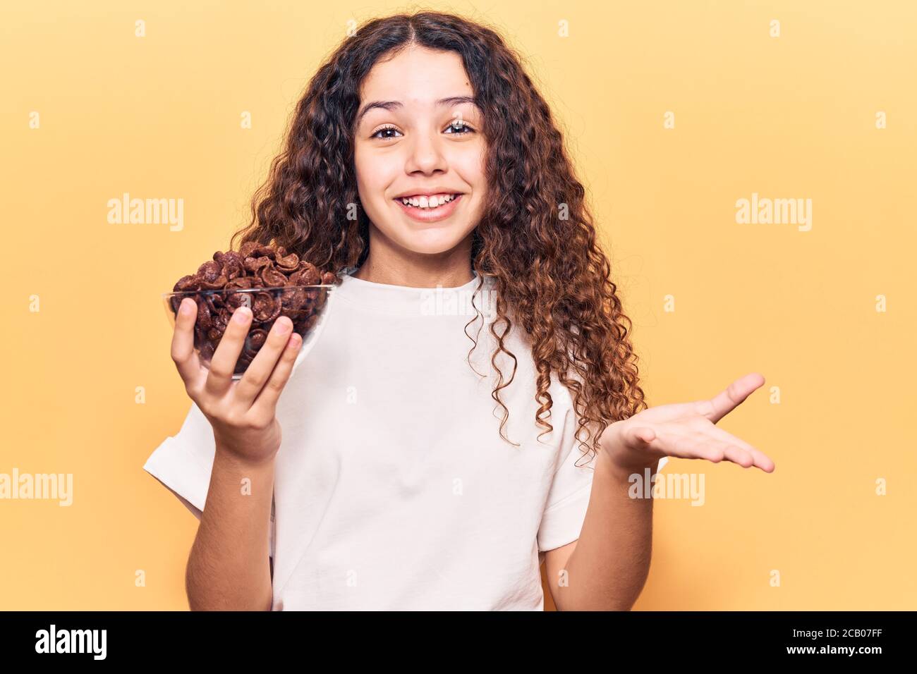 Beautiful kid girl with curly hair holding chocolate cereals ...