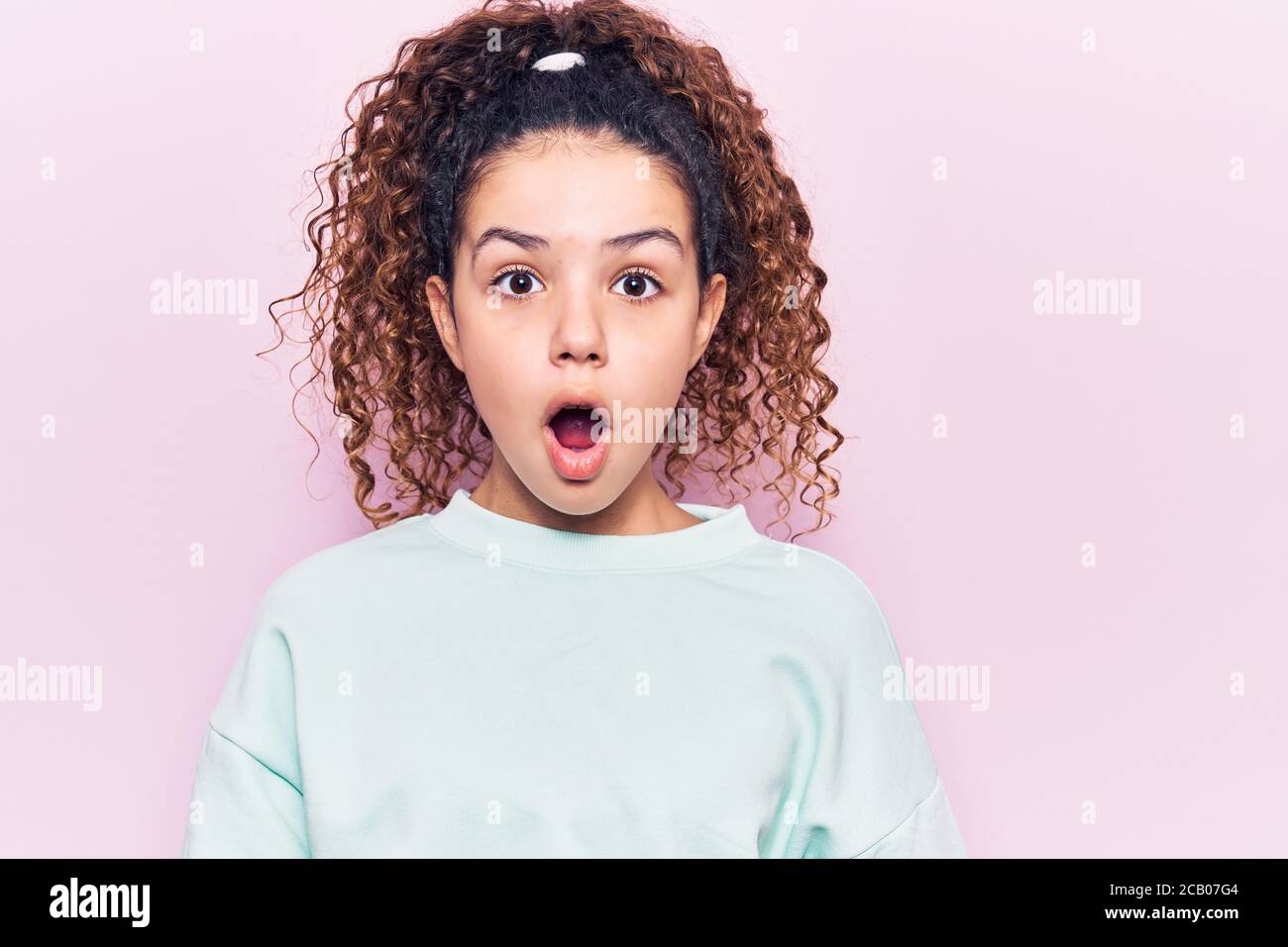 Beautiful kid girl with curly hair wearing casual clothes scared and ...