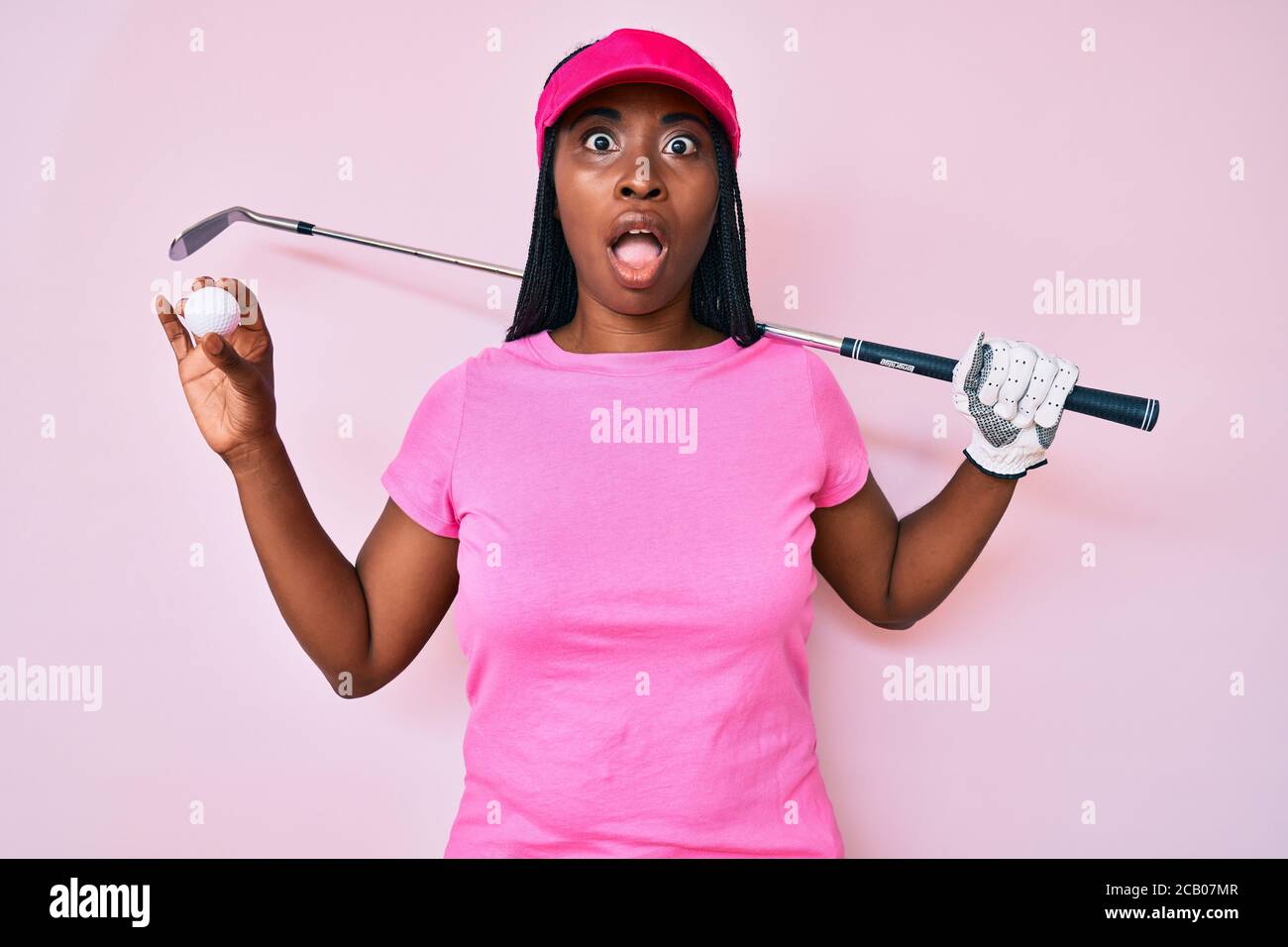 African american golfer woman with braids holding golf ball afraid and ...