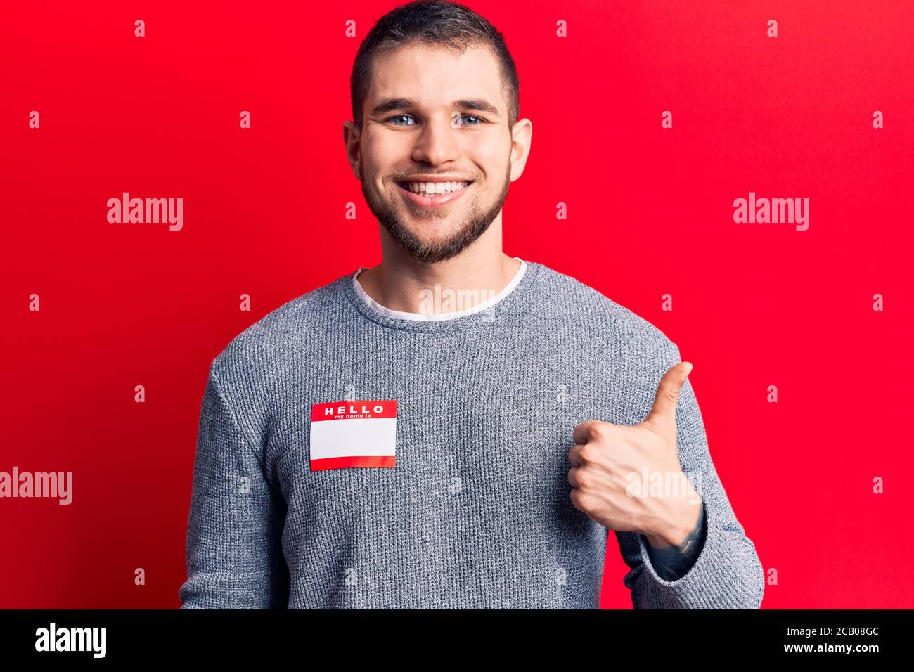 Young handsome man wearing hello my name is sticker smiling happy and ...